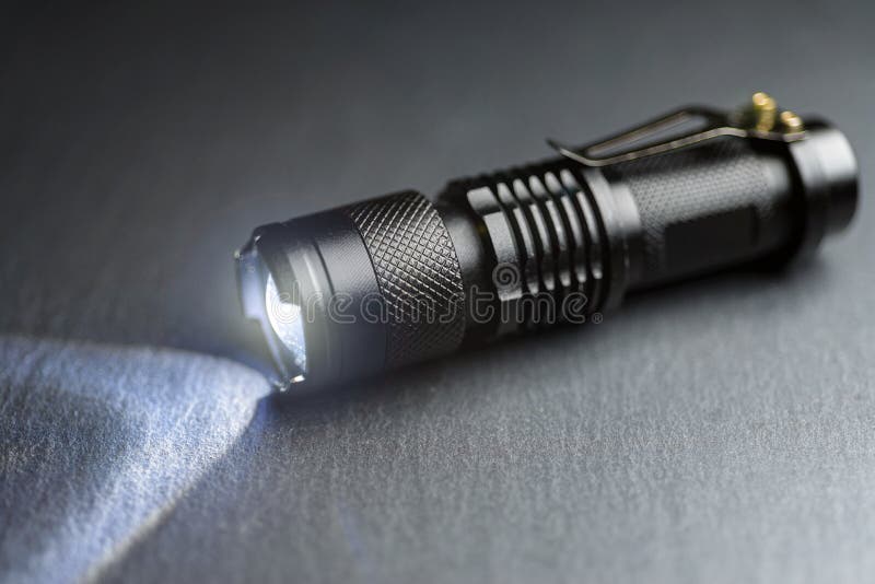 Tactical Waterproof Flashlight. LED Flashlight Shines on the Table in ...