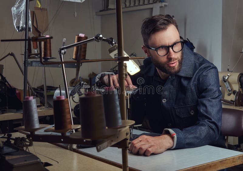 Tailor Sitting at Table with Sewing Machine and Looking at a Camera in ...