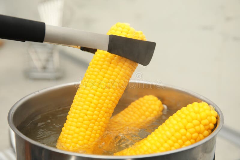 Taking Boiled Corn from Pot with Tongs in Kitchen, Closeup Stock Image ...
