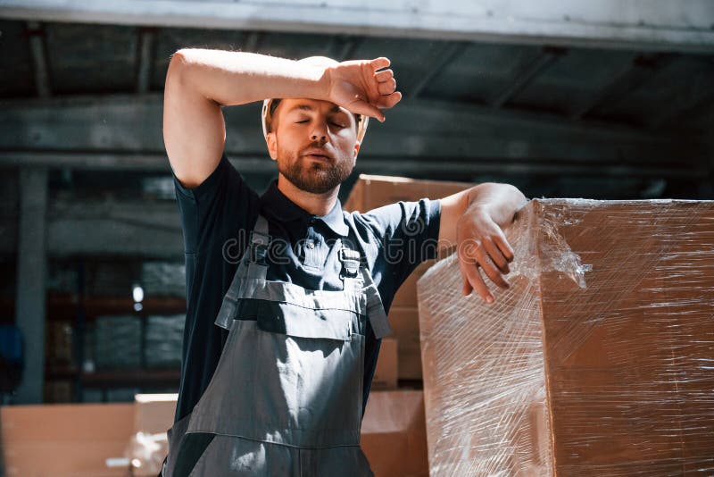 Taking a Break. Tired Employee in Uniform is Working in the Storage at ...