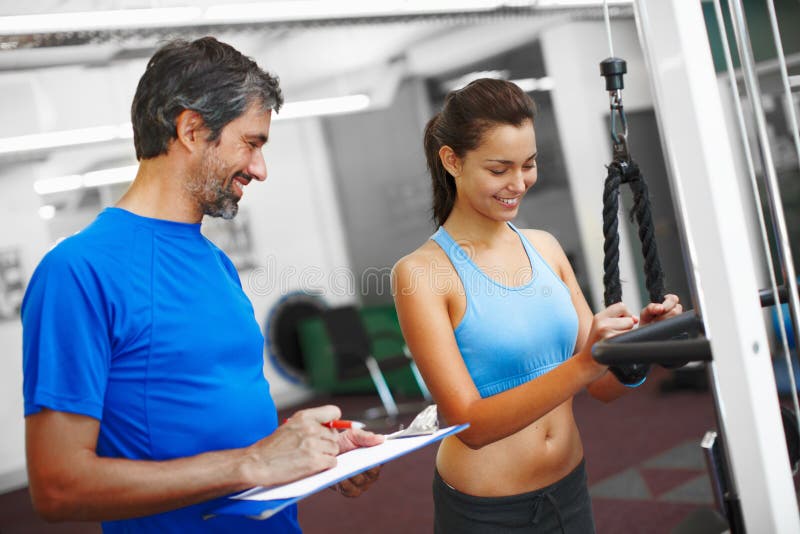 Taking Notes. an Attractive Young Woman Exercising in the Gym while Her ...