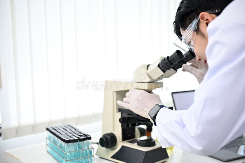 Talented Asian Male Scientist or Chemist Looking Under the Microscope ...