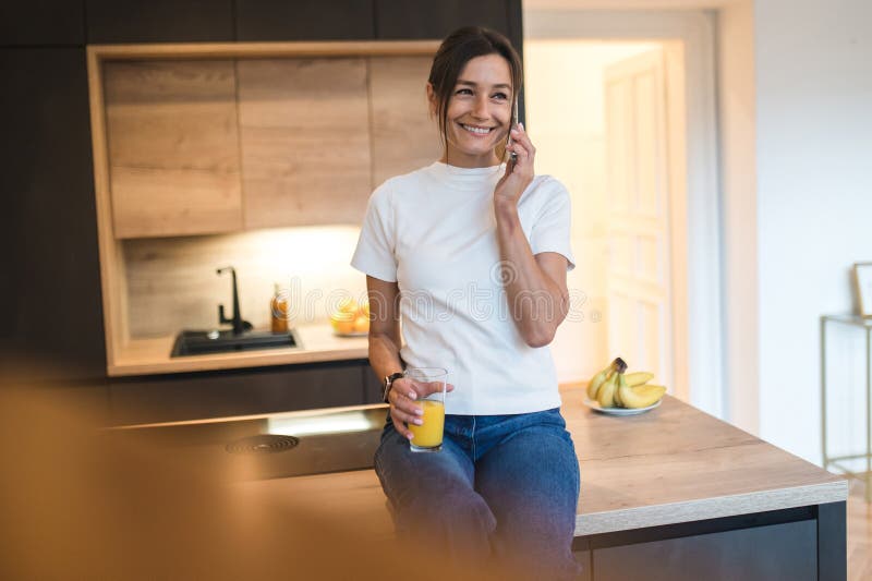 Smiling Dark-haired Woman Talking on the Phone in the Kitchen Stock ...