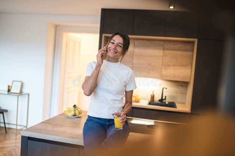 Smiling Dark-haired Woman Talking on the Phone in the Kitchen Stock ...