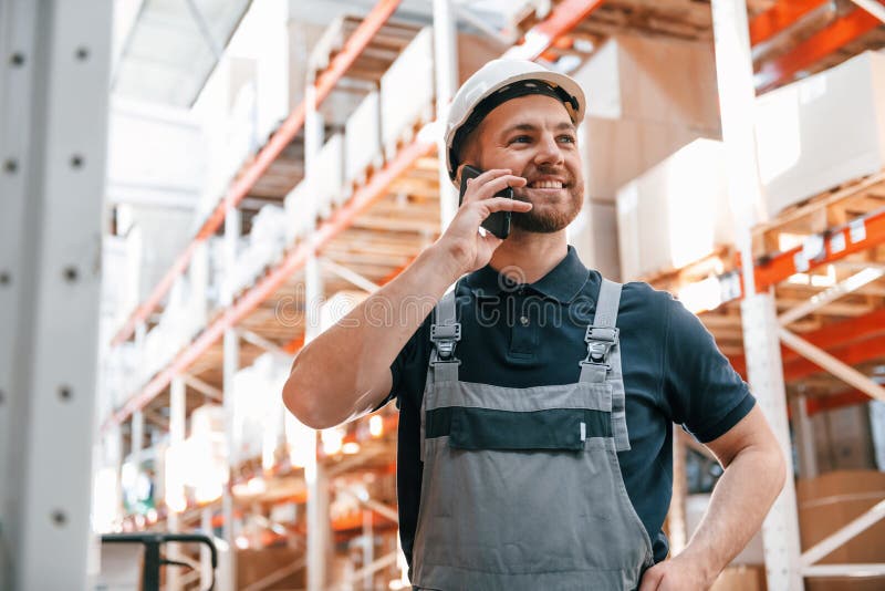 Talking by Phone. Employee in Uniform is Working in the Storage at ...