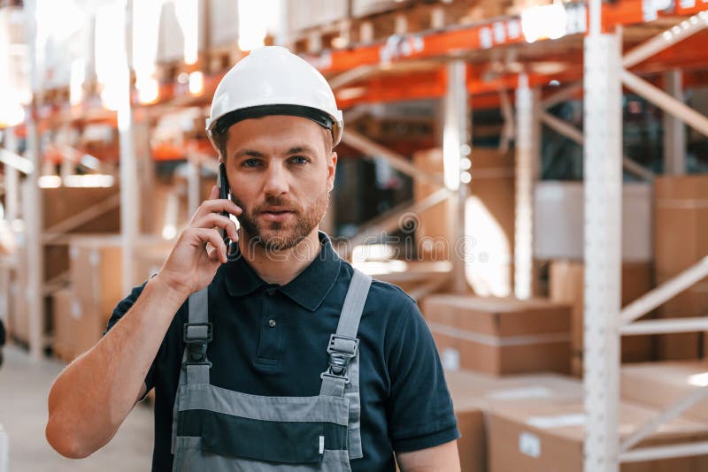 Talking by Phone. Employee in Uniform is Working in the Storage at ...