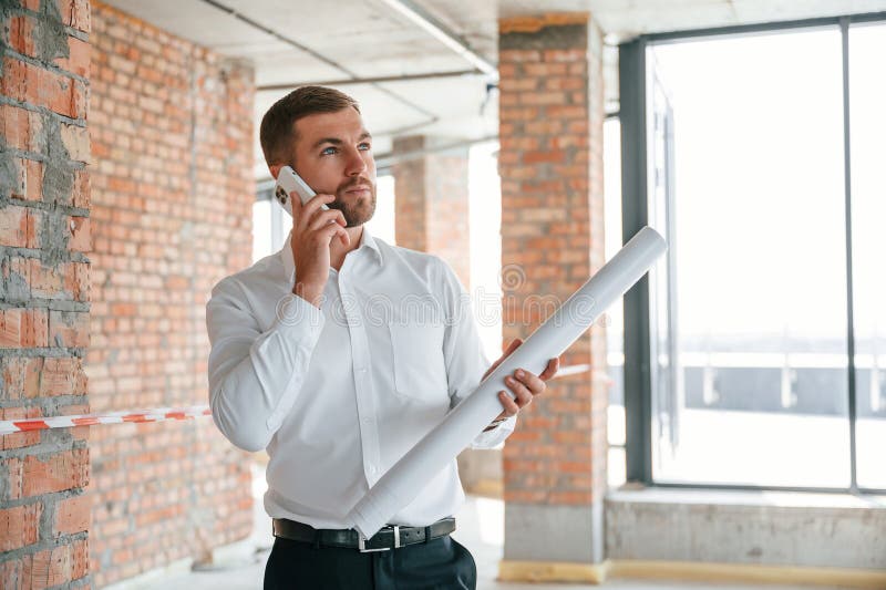Talking by Phone. Man in White Shirt is Working Indoors at Construction ...
