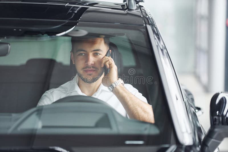 Talks by Phone. Young Man in White Shirt is Sitting Inside of a Modern ...