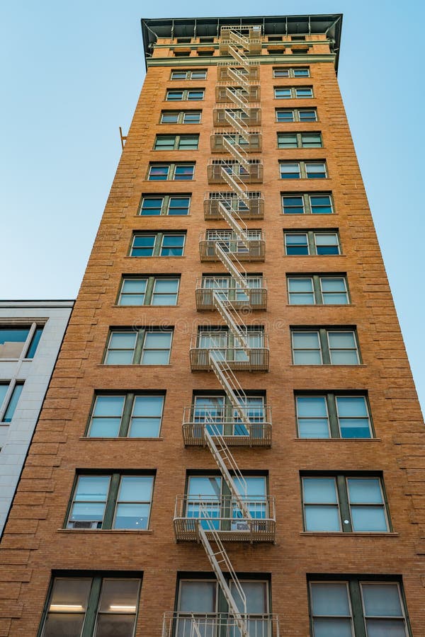 Tall Brick Building with External Fire Escape Against a Clear Blue Sky ...