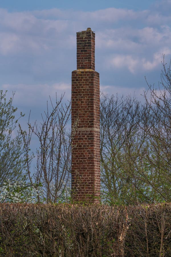 A Tall Brick Chimney Juts Out from Behind a Hedge. Stock Image - Image ...