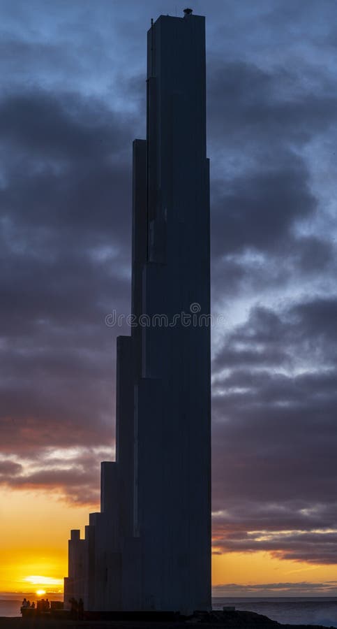 A Tall Building with a Large Shadow Cast on it. the Sky is Dark and ...