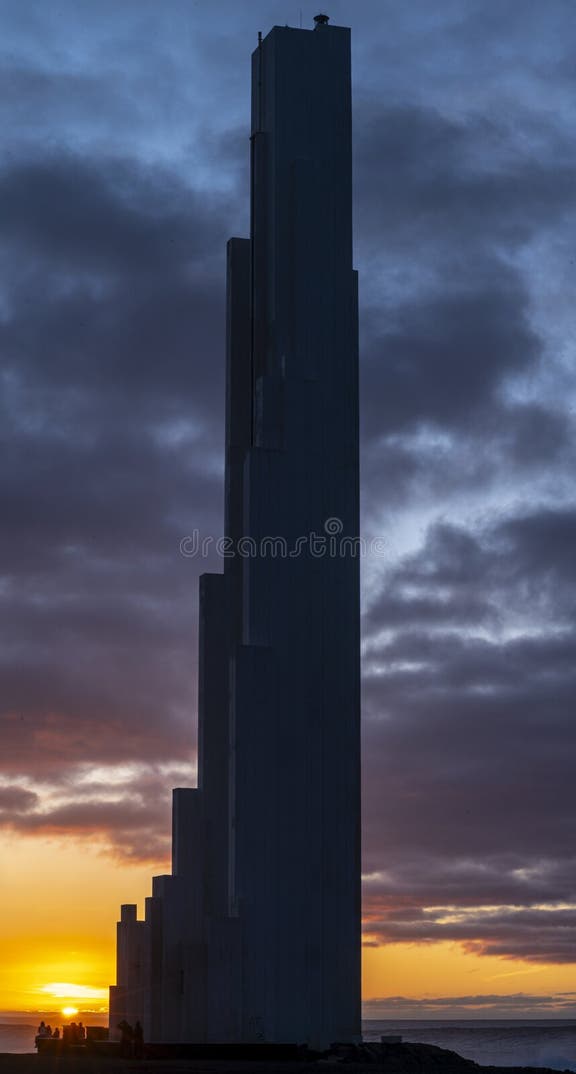 A Tall Building with a Large Shadow Cast on it. the Sky is Dark and ...