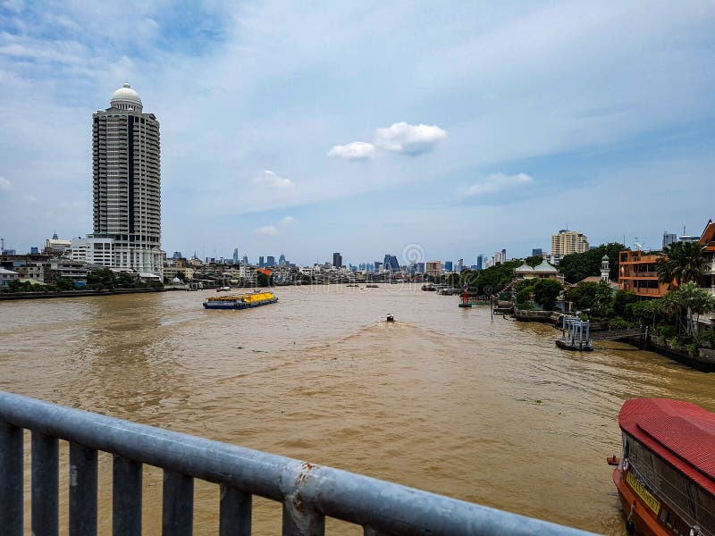 A Tall Building Next To the River with Boats in Bangkok Stock Photo ...