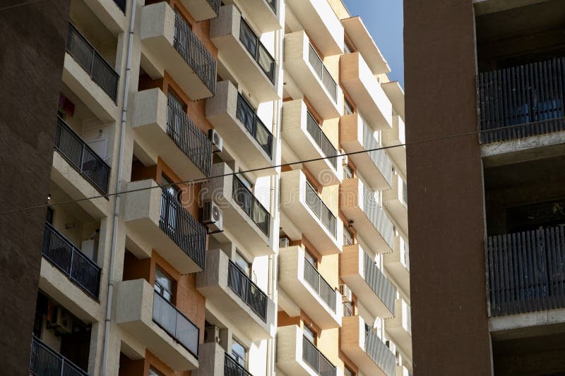 A Tall Building with Windows, Next To Which Workers Stand on a Crane ...
