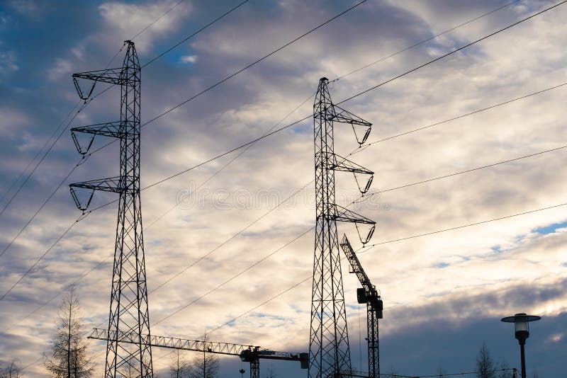 A Tall Construction Crane Against the Setting Sun. High Voltage Power ...