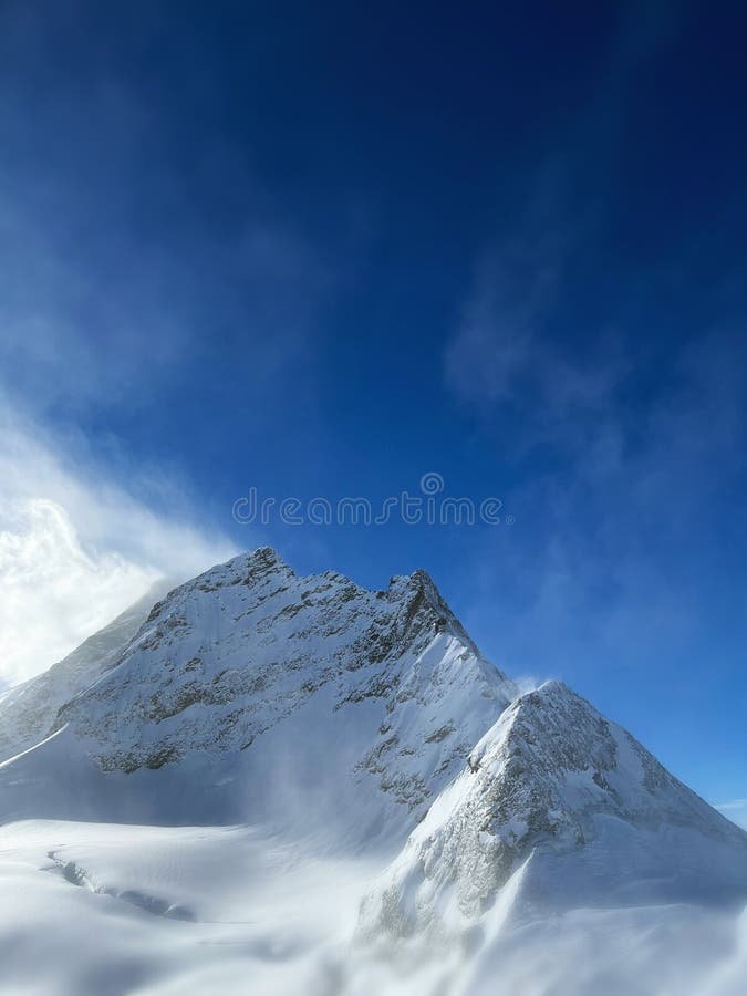 Tall Mountain Covered in Snow with Its Peak in the Clouds Stock Photo ...