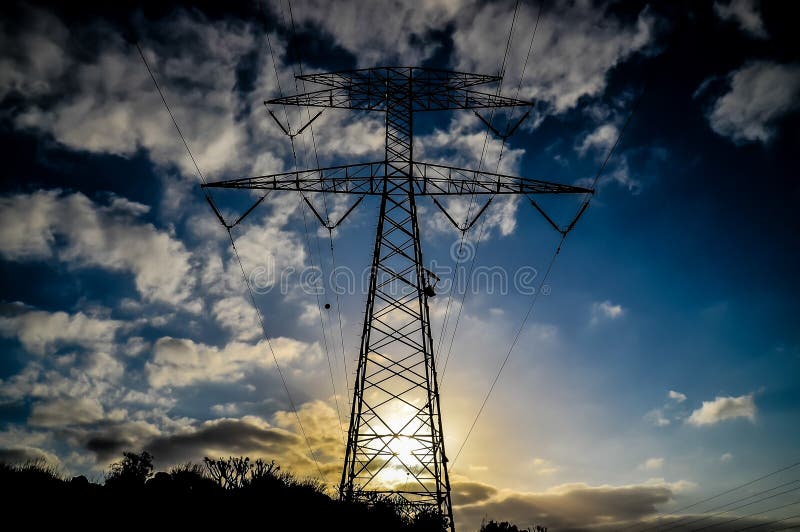 A Tall Power Line Tower is Silhouetted Against a Blue Sky Stock Image ...