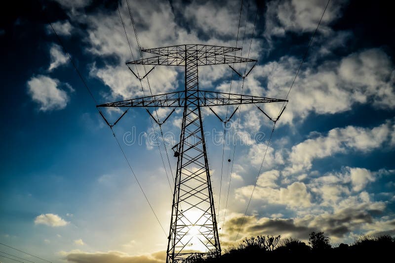 A Tall Power Line Tower is Silhouetted Against a Blue Sky Stock Photo ...