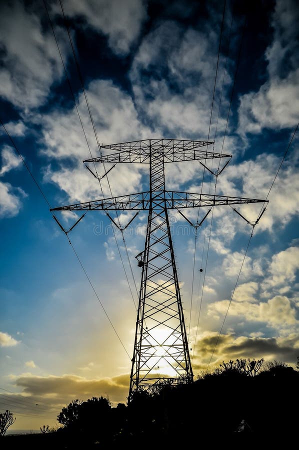 A Tall Power Line Tower is Silhouetted Against a Blue Sky Stock Image ...