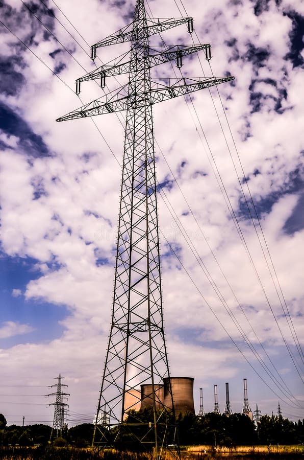 A Tall Power Tower is Surrounded by Power Lines and a Large Building ...
