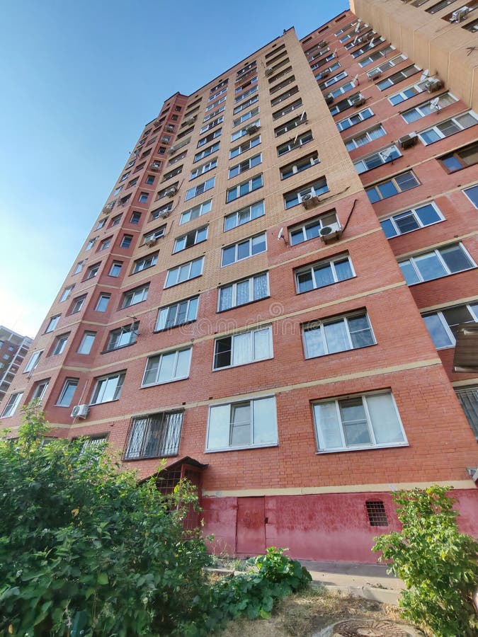 A Tall Red and Beige Brick Residential Building with Multiple Balconies ...