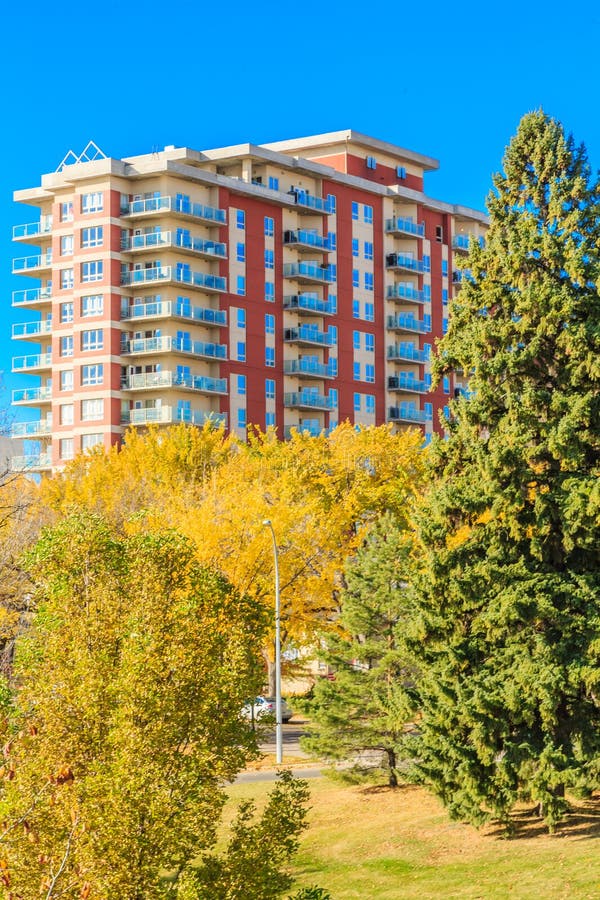 A Tall Red Building with a Green Tree in Front of it Stock Image ...