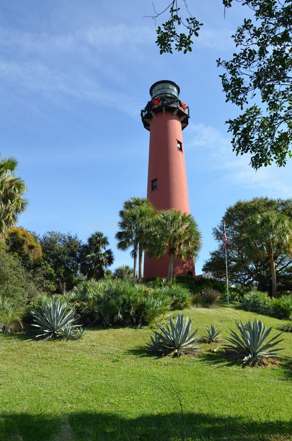 Tall Red Lighthouse with Green Grass and Trees Stock Photo - Image of ...