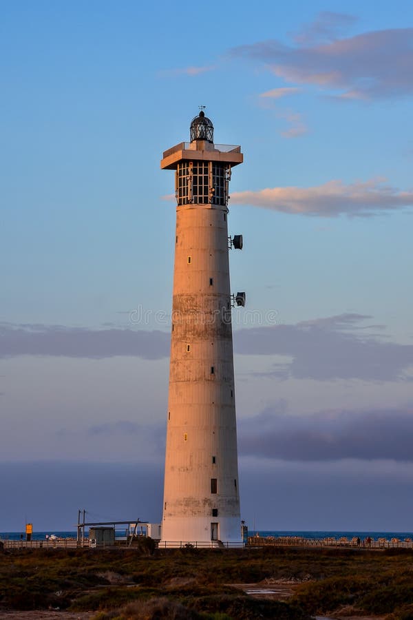A Tall White Lighthouse is Standing on a Beach Stock Photo - Image of ...