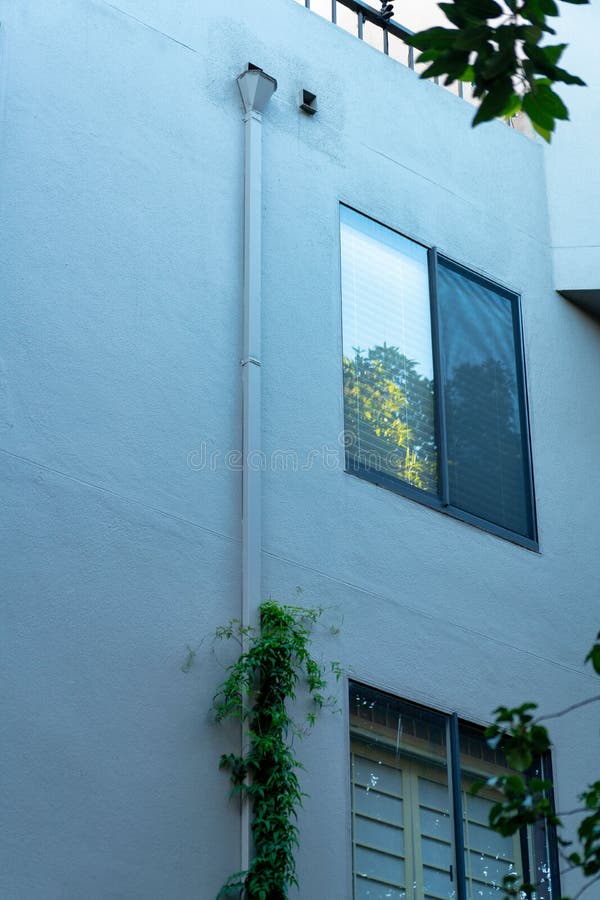 Tall White Rain Gutter on Side of Stucco Beige Building in Midday Shade ...