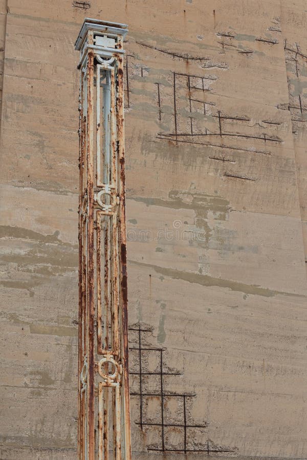 Tall Wrought Iron Post with Rust and Gray Paint Against a Crumbling ...