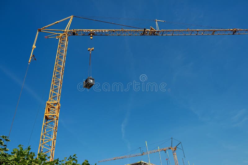 A Tall Yellow Construction Crane with a Dangling Black Box Against a ...