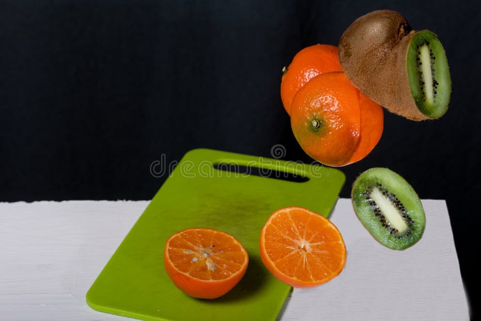 Tangerines and Kiwis Float Above the Table Surface. Some are Cut into ...