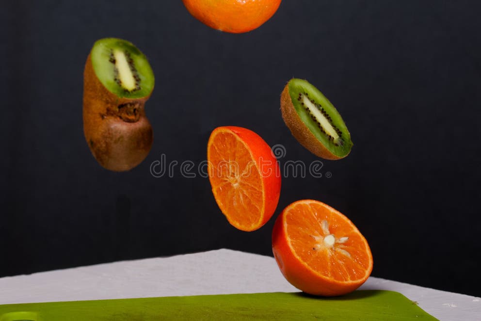 Tangerines and Kiwis Float Above the Table Surface. Some are Cut into ...