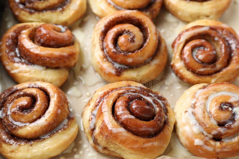Tasty Cinnamon Rolls with Cream on Parchment Paper, Closeup Stock Photo ...