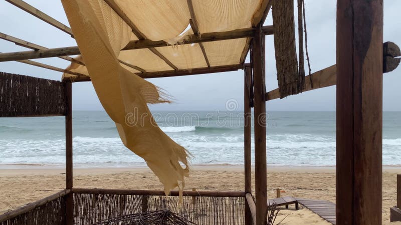 Tattered Canopy Flutters in the Wind, Empty Beach with Gentle Ocean ...