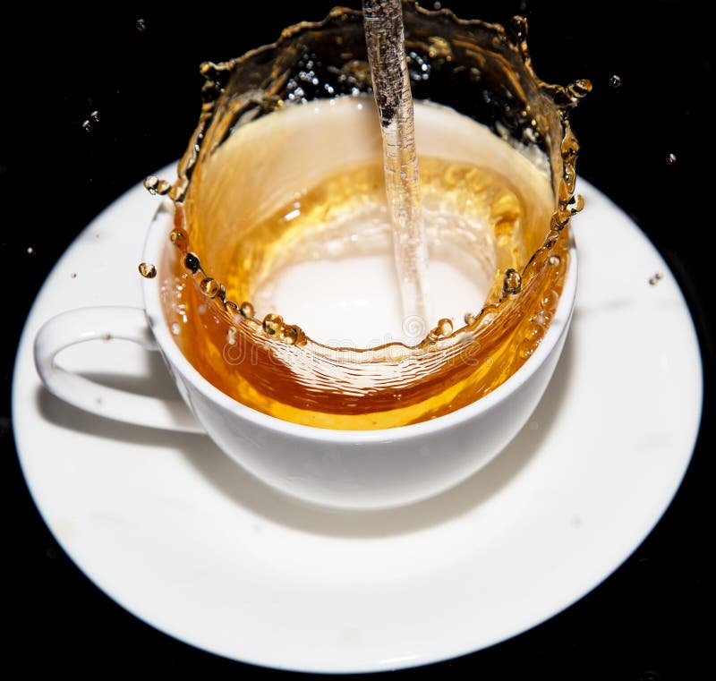 Tea Being Poured into a Saucer with Splashes on a Black Background ...