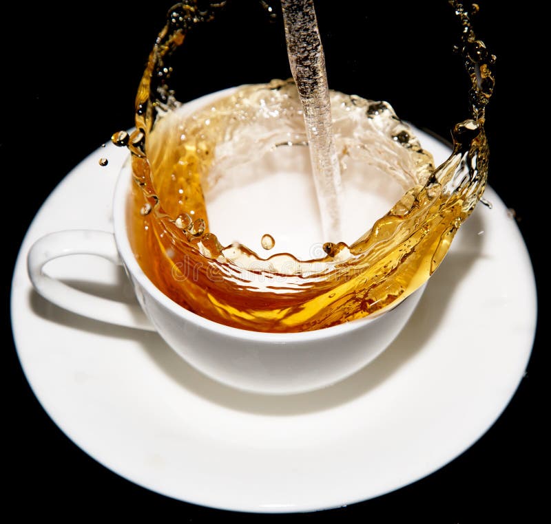 Tea Being Poured into a Saucer with Splashes on a Black Background ...