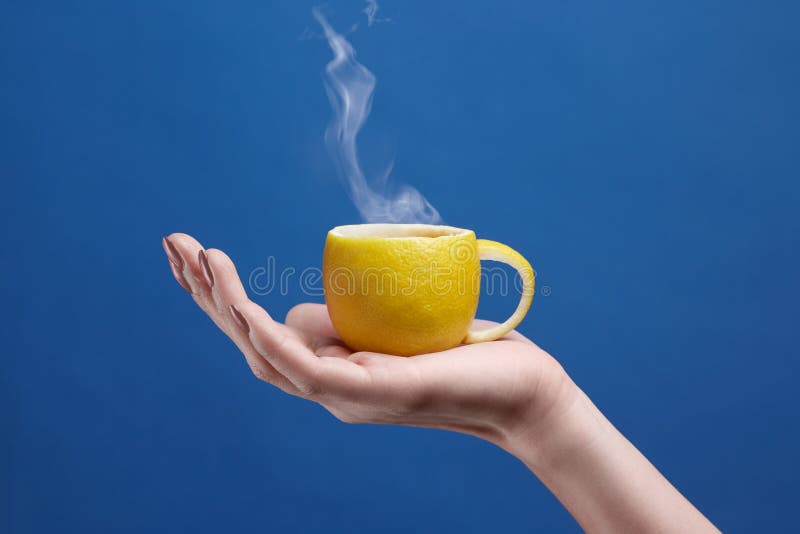 A Tea Cup Made of Lemon. Lemon Cup in Hand on a Blue Background Stock ...