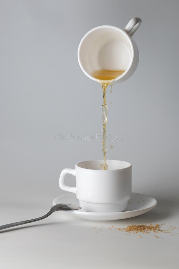 Tea Pouring from a White Cup into Another One Standing on the Table ...