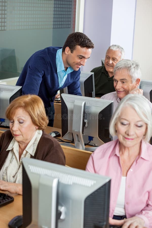 Teacher Assisting Senior Students in Computer Class Stock Image - Image ...
