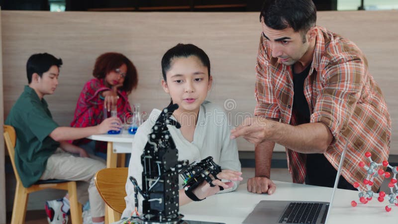 Teacher Assists Student Constructing Robotic Arm in Classroom for ...