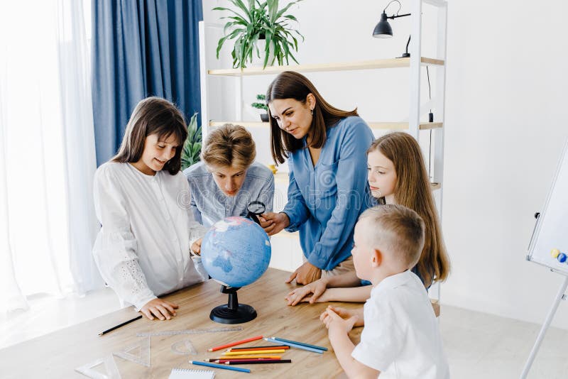 Teacher and Children in Class are Looking at Globe, Teacher Helps ...
