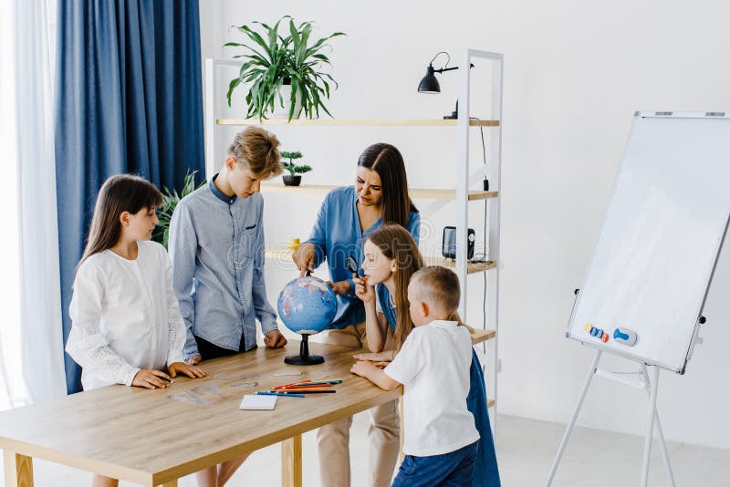 Teacher and Children in Class are Looking at Globe, Teacher Helps ...