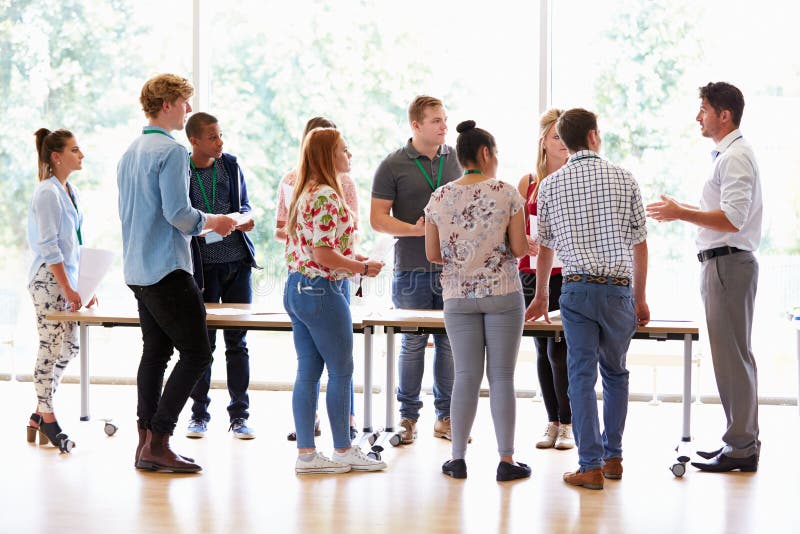 Teacher with College Students Standing by Desks in Classroom Stock ...