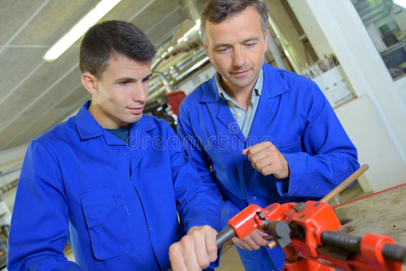 Teacher Encouraging Apprentice Using Machinery Stock Image - Image of ...