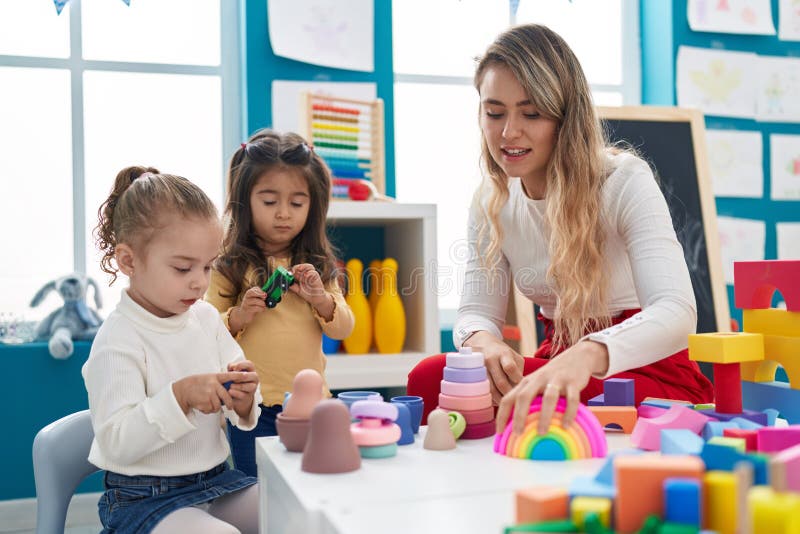 Teacher with Girls Playing with Geometry Blocks Sitting on Table at ...