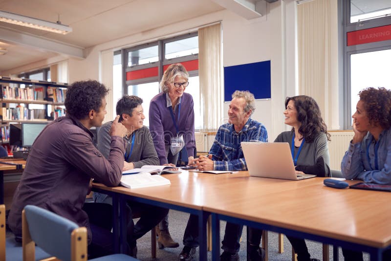 Teacher with Group of Mature Adult Students in Class Sit Around Table ...