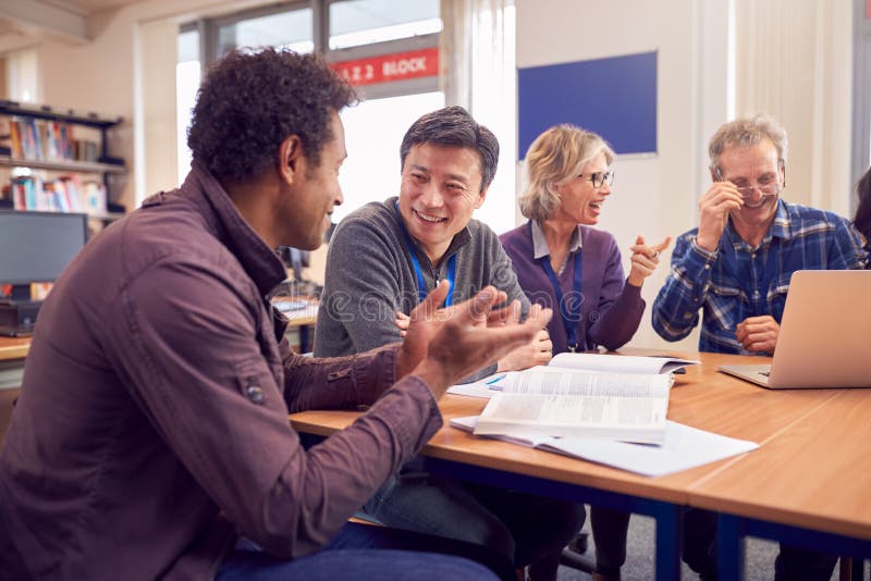 Teacher with Group of Mature Adult Students in Class Sit Around Table ...
