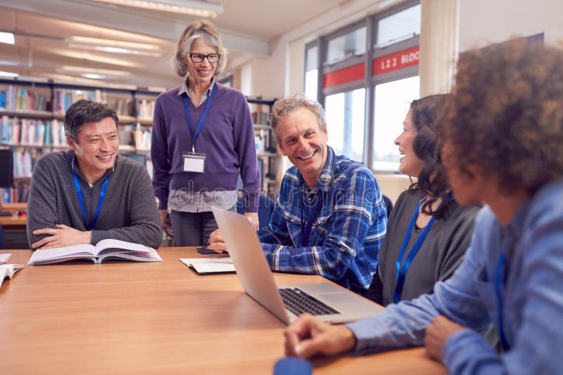 Teacher with Group of Mature Adult Students in Class Sit Around Table ...