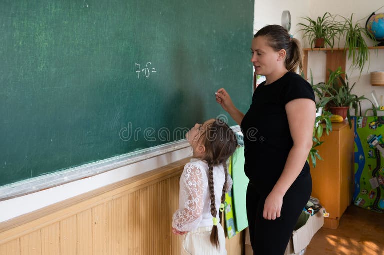 Teacher Guides Student through Math Problem on the Chalkboard. Child is ...